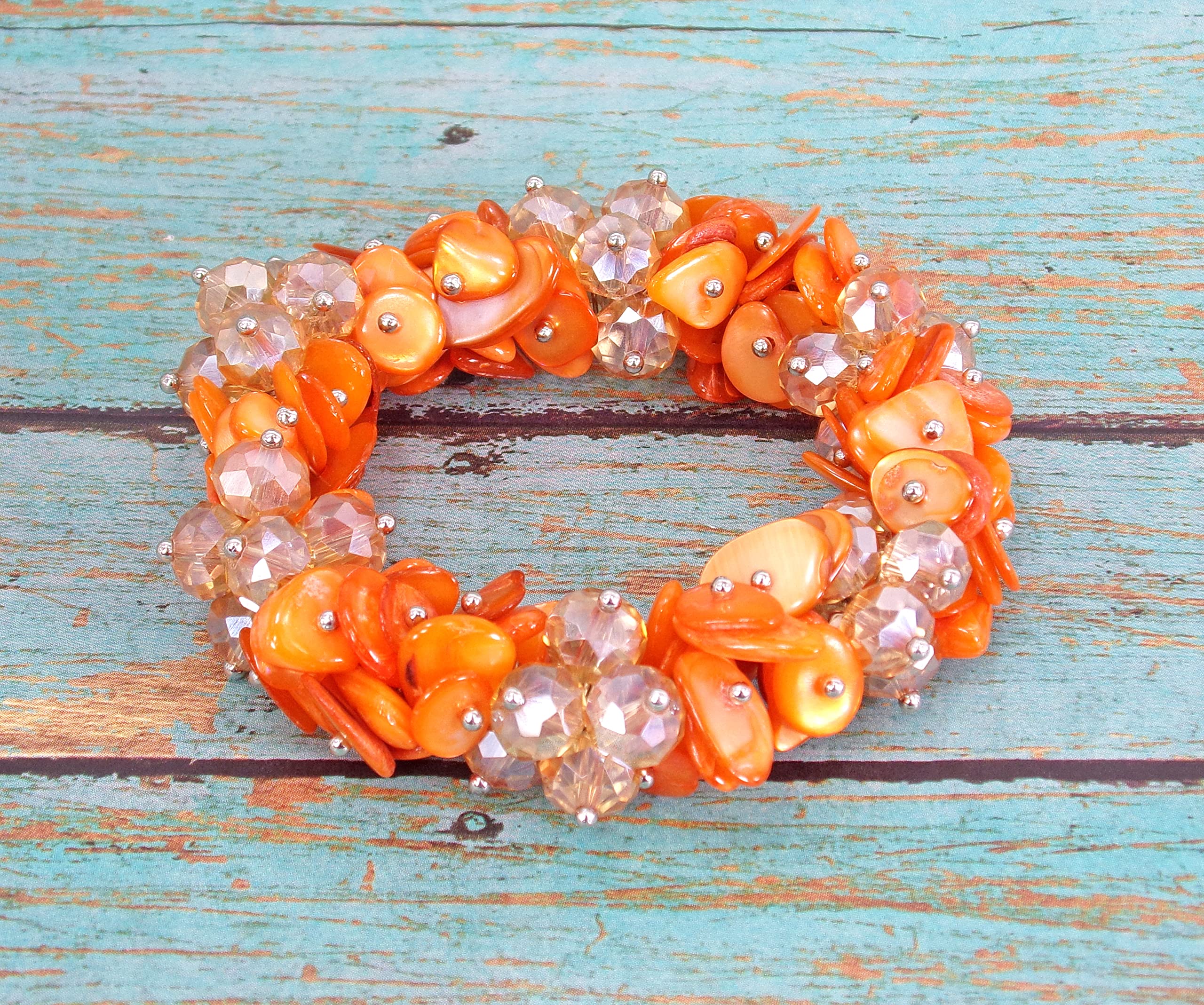 Calisa Designs Woman's orange shell and glass beaded stretch bracelet with silver beads, Designed with clusters of orange shell and orange facet cut glass beads.