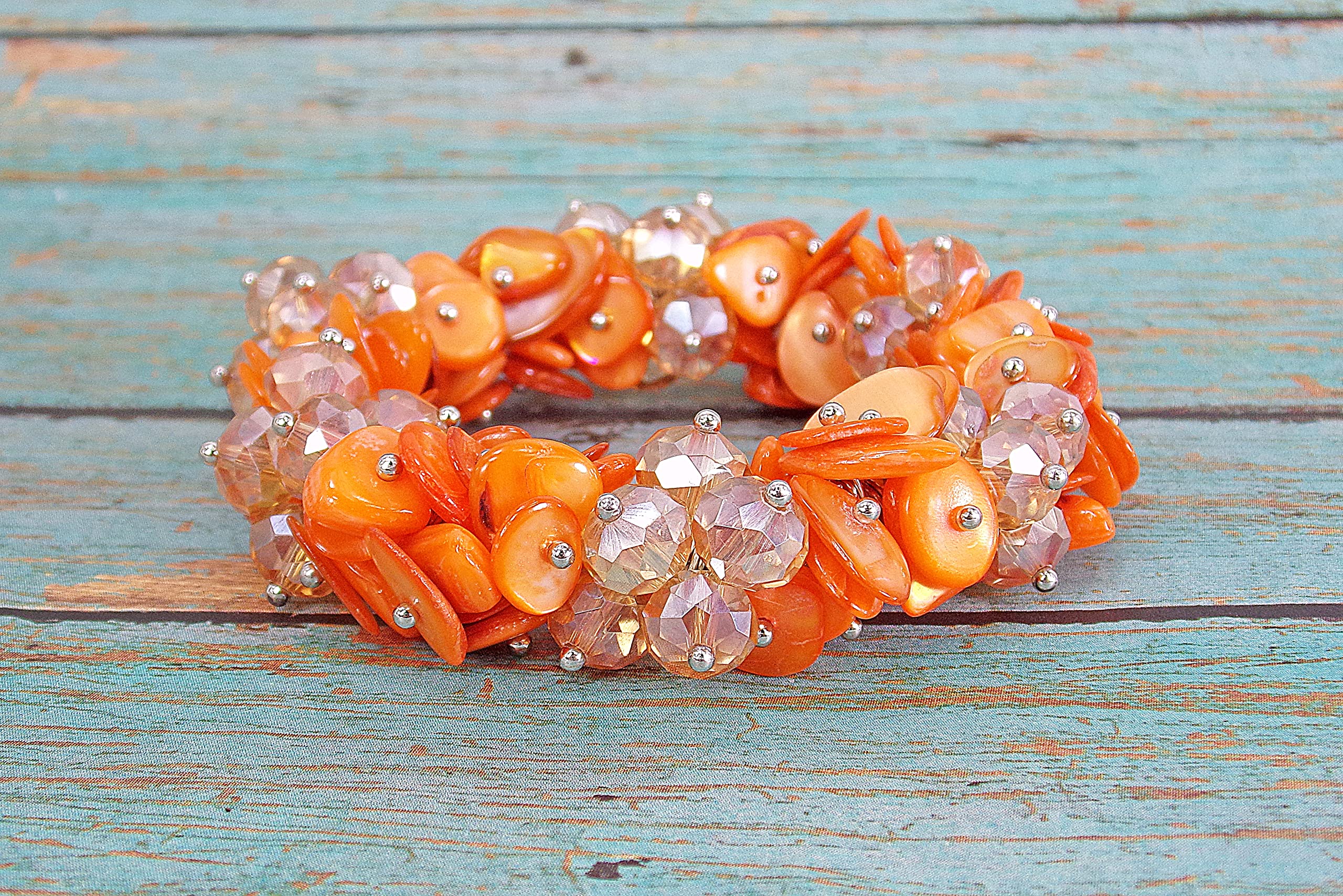 Calisa Designs Woman's orange shell and glass beaded stretch bracelet with silver beads, Designed with clusters of orange shell and orange facet cut glass beads.