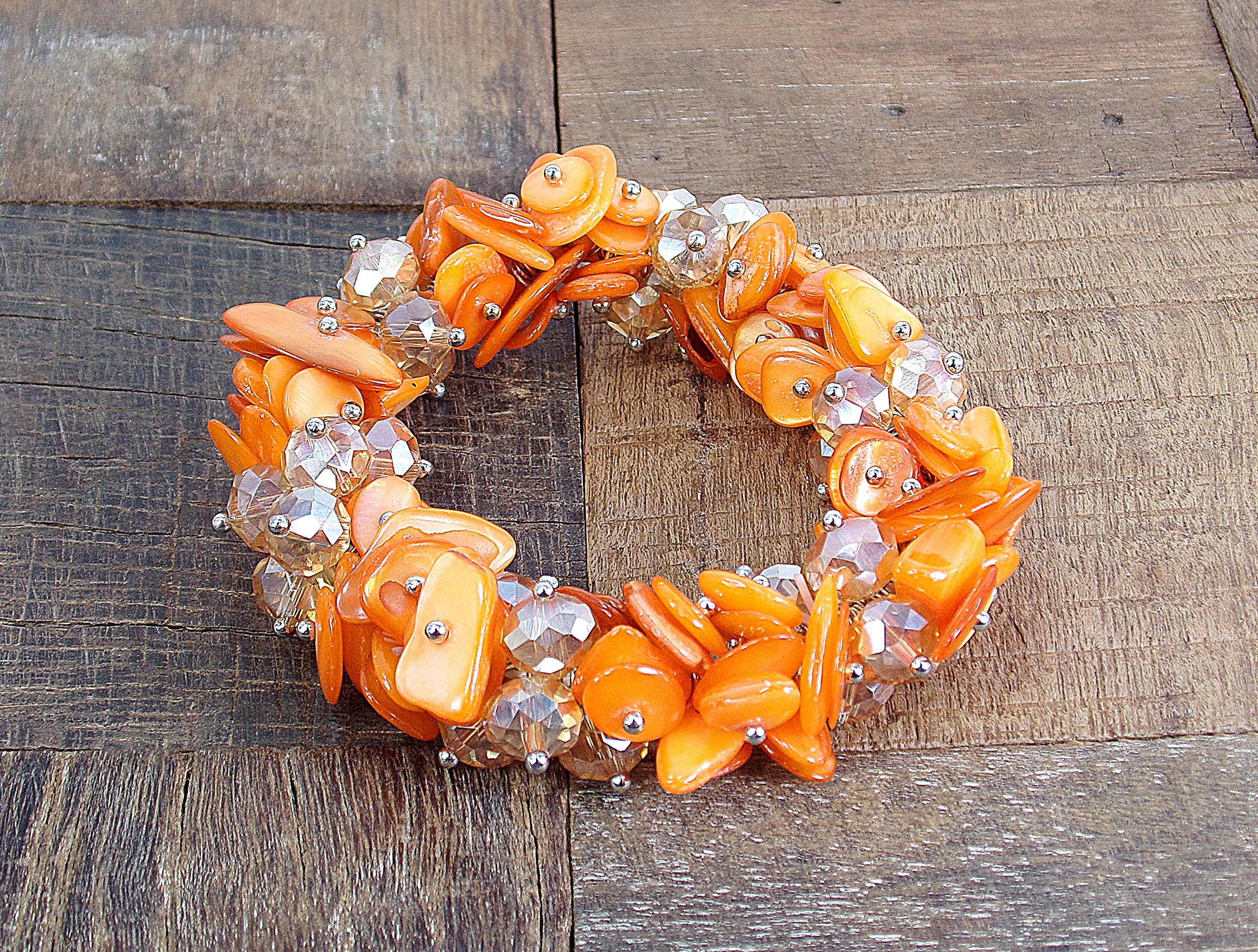 Calisa Designs Woman's orange shell and glass beaded stretch bracelet with silver beads, Designed with clusters of orange shell and orange facet cut glass beads.