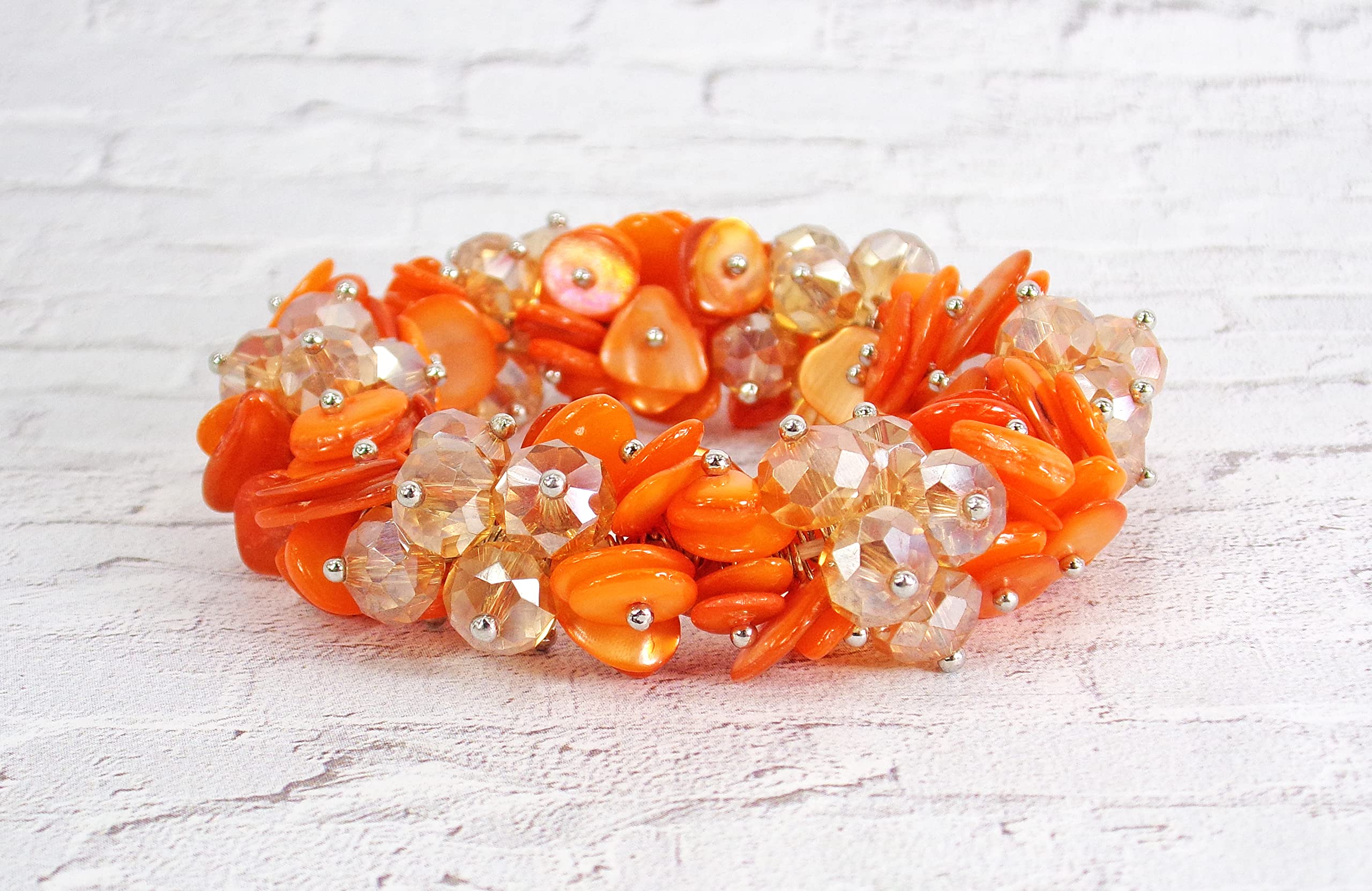 Calisa Designs Woman's orange shell and glass beaded stretch bracelet with silver beads, Designed with clusters of orange shell and orange facet cut glass beads.