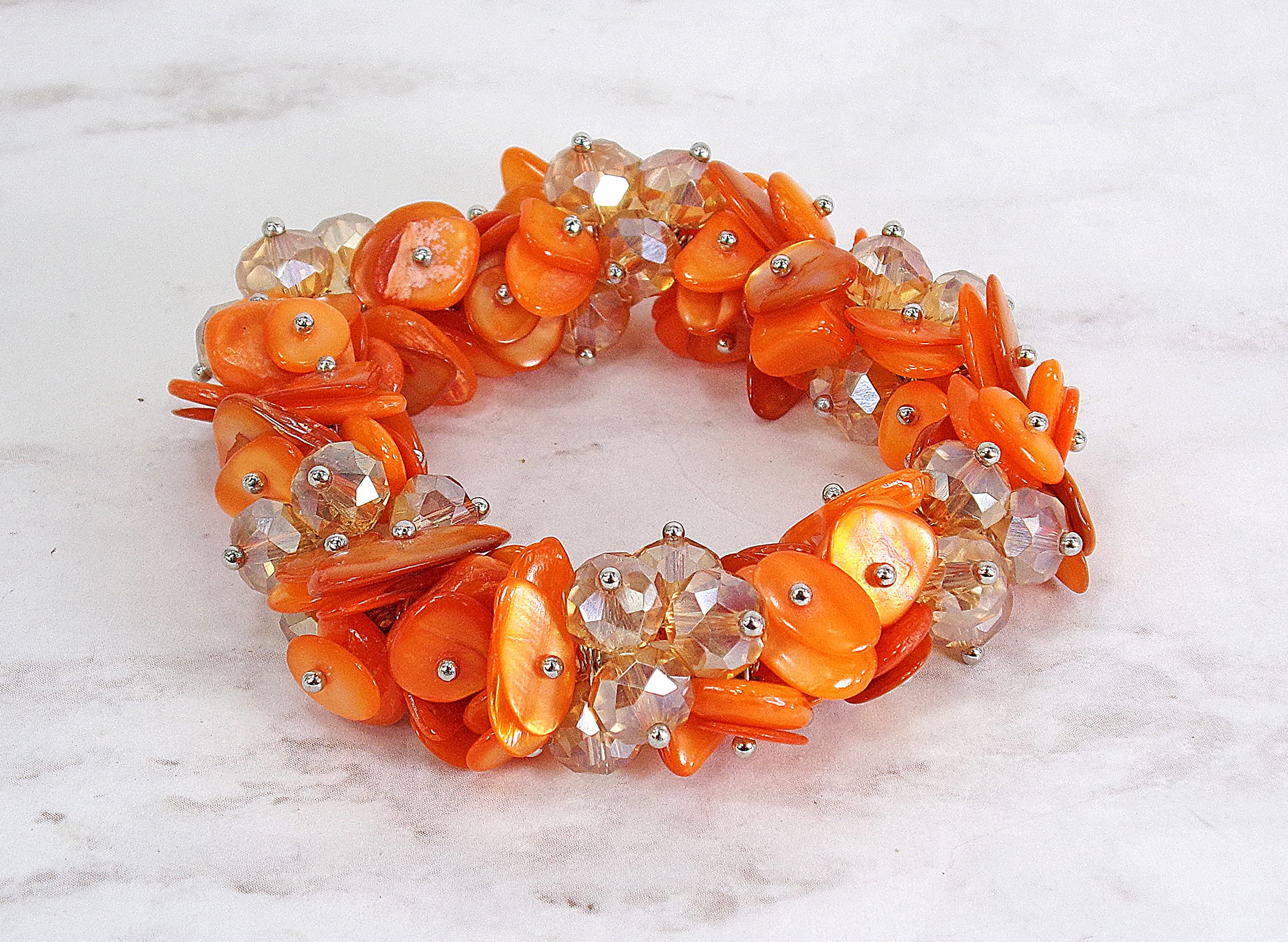 Calisa Designs Woman's orange shell and glass beaded stretch bracelet with silver beads, Designed with clusters of orange shell and orange facet cut glass beads.